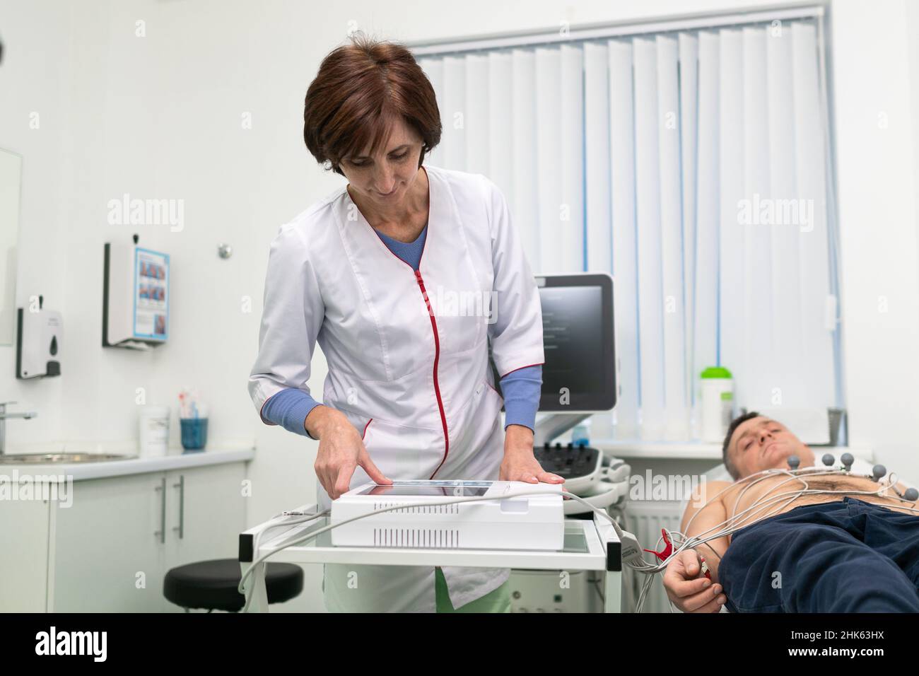 ECG concept. Woman doctor cardiologist doing electrocardiogram test to ...