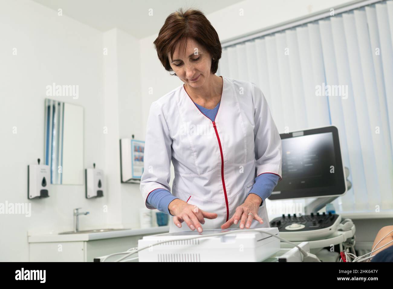 Cardiologist doctor performs electrocardiography procedure on man lying ...