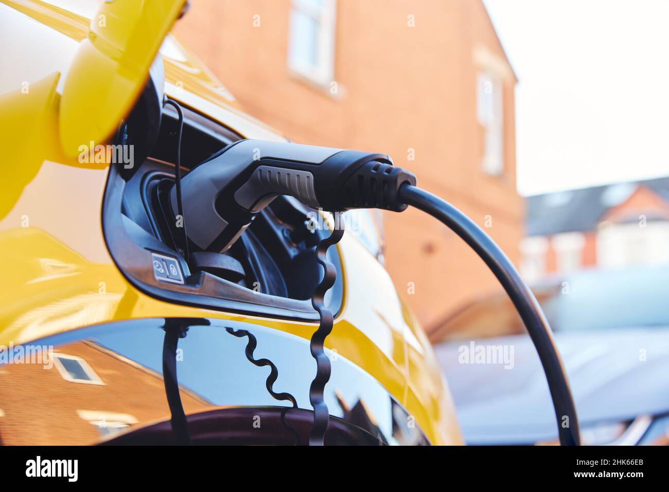 Electric car plugged in outside house on street Stock Photo - Alamy