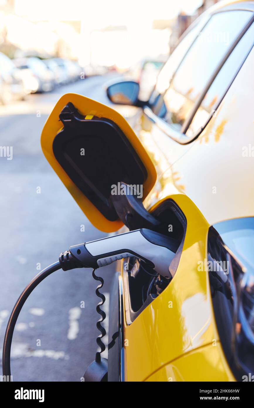 Electric car plugged in outside house on street Stock Photo - Alamy