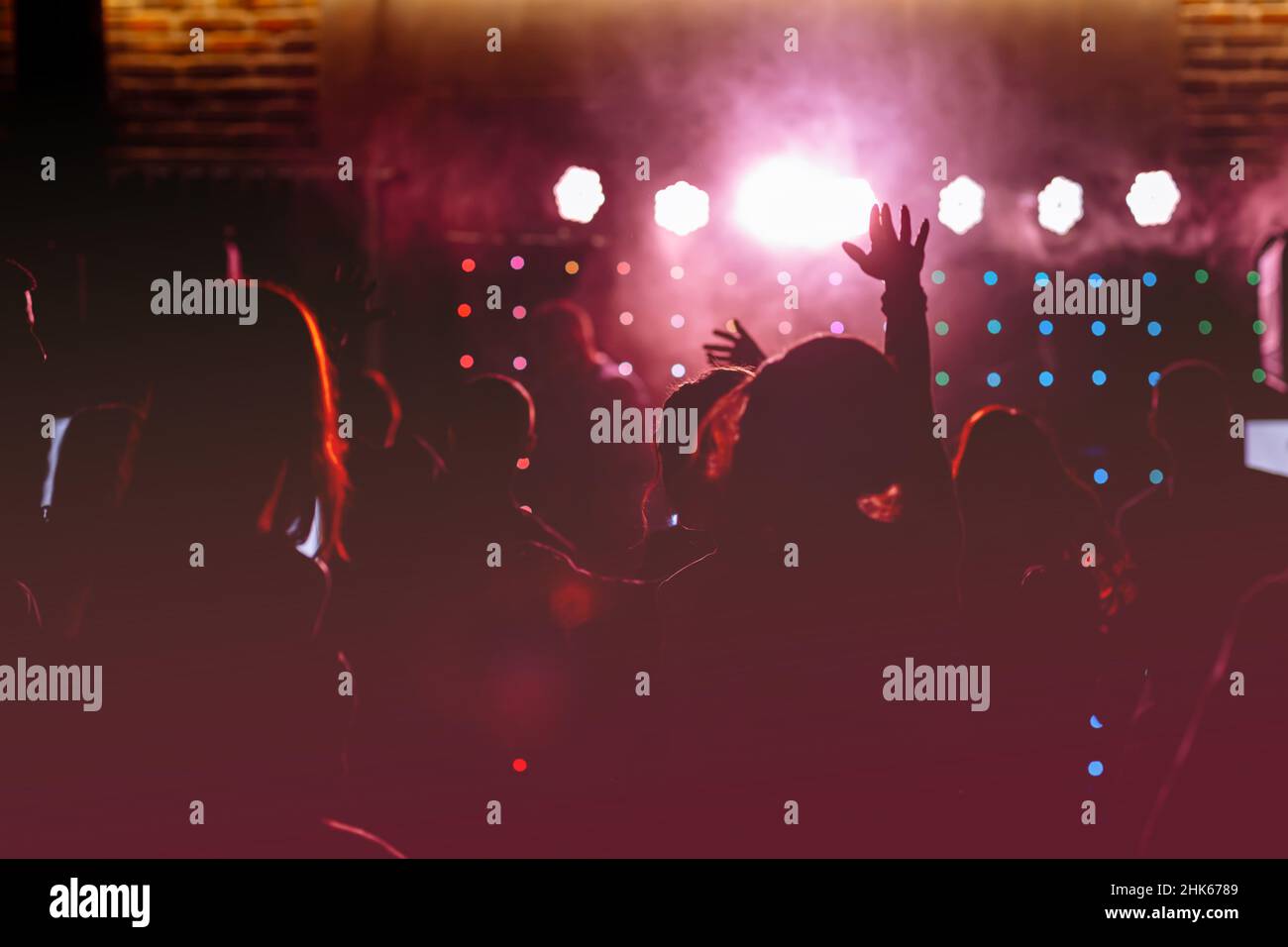 cheering crowd in front of bright red stage lights. Silhouette image of ...
