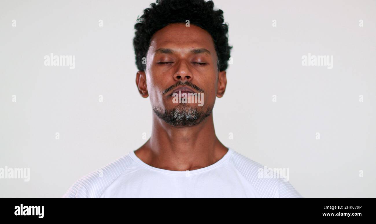 African man closing eyes trying to relax and contemplate life in ...