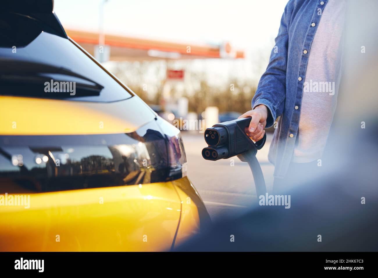 Man plugging electric car in at a EV charging station using a rapid ...