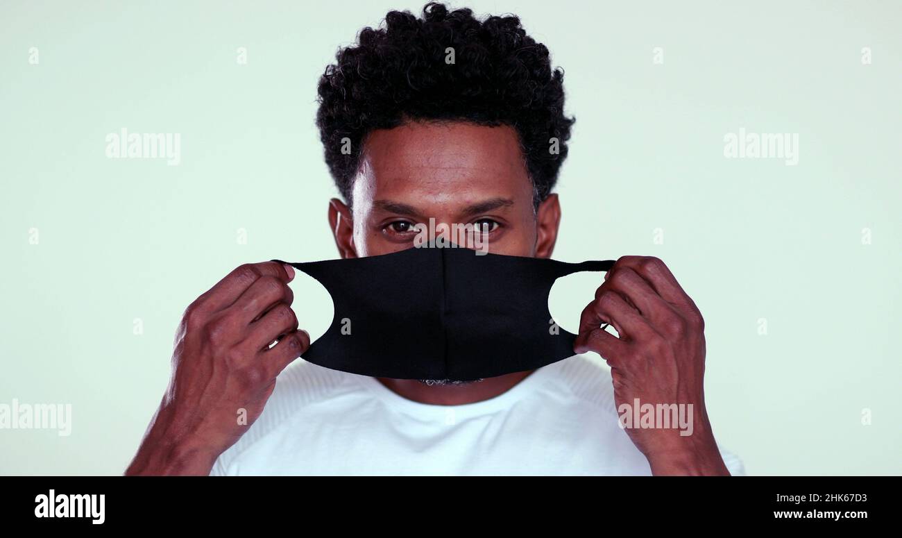 African person removing mask feeling relief Stock Photo - Alamy