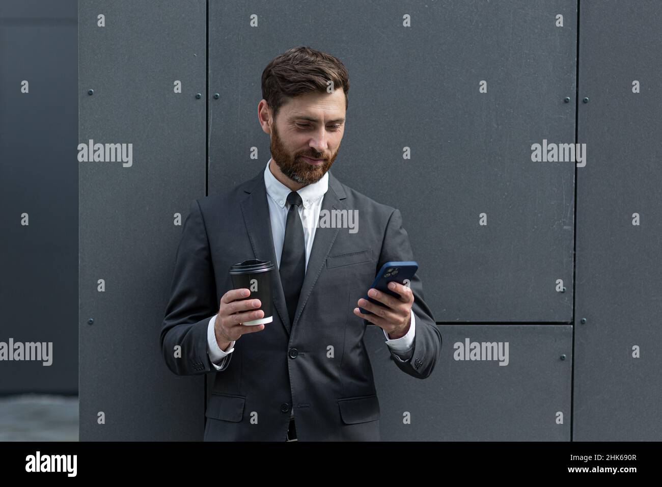 Bearded businessman in formal suit on break using mobile phone use ...