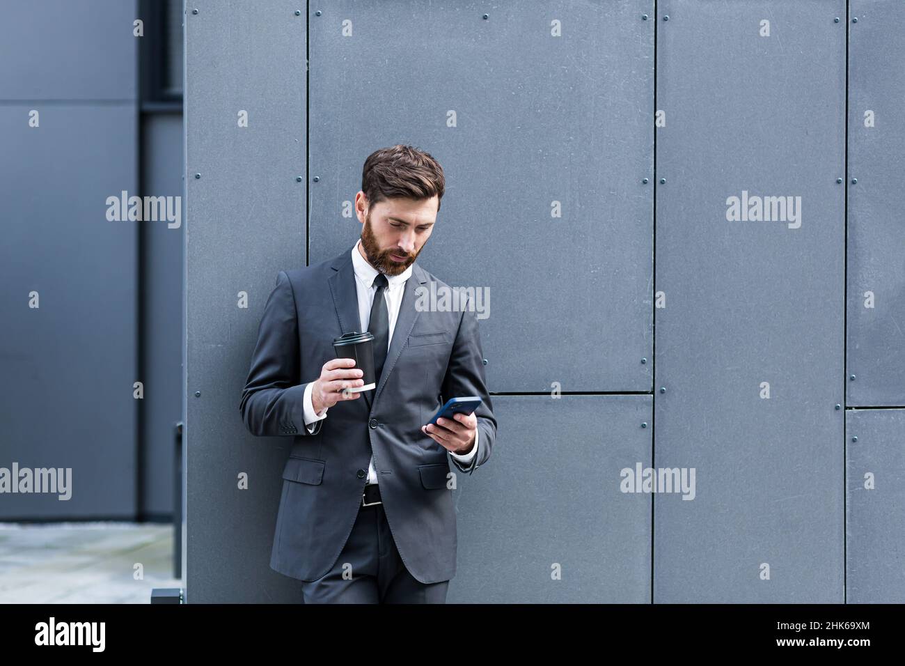 Caucasian bearded employee on urban background office building texting ...