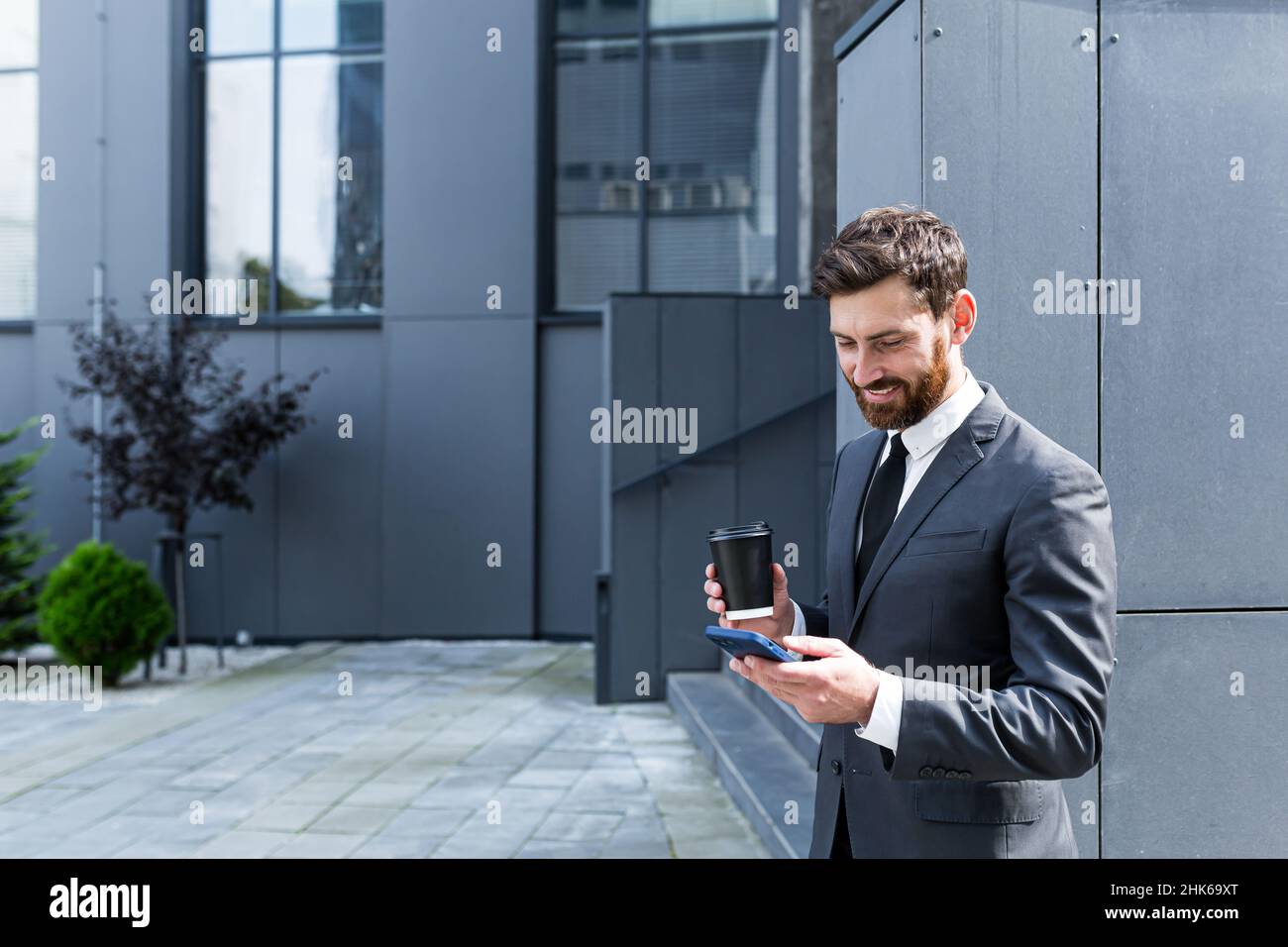 Caucasian bearded employee on urban background office building texting ...