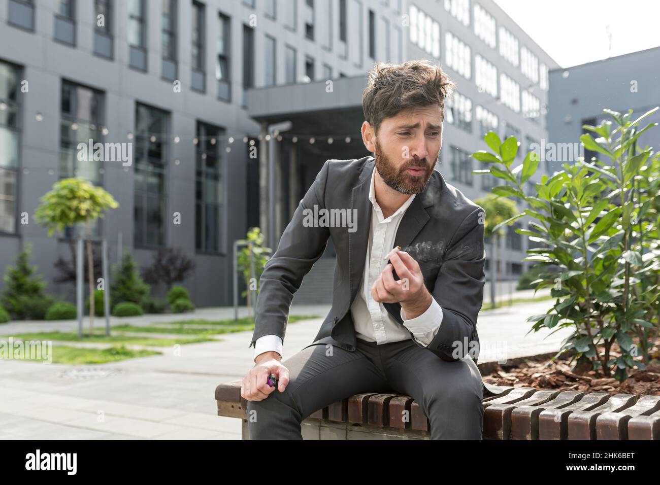 Male businessman smoking cigarette in the air near the office relieves ...
