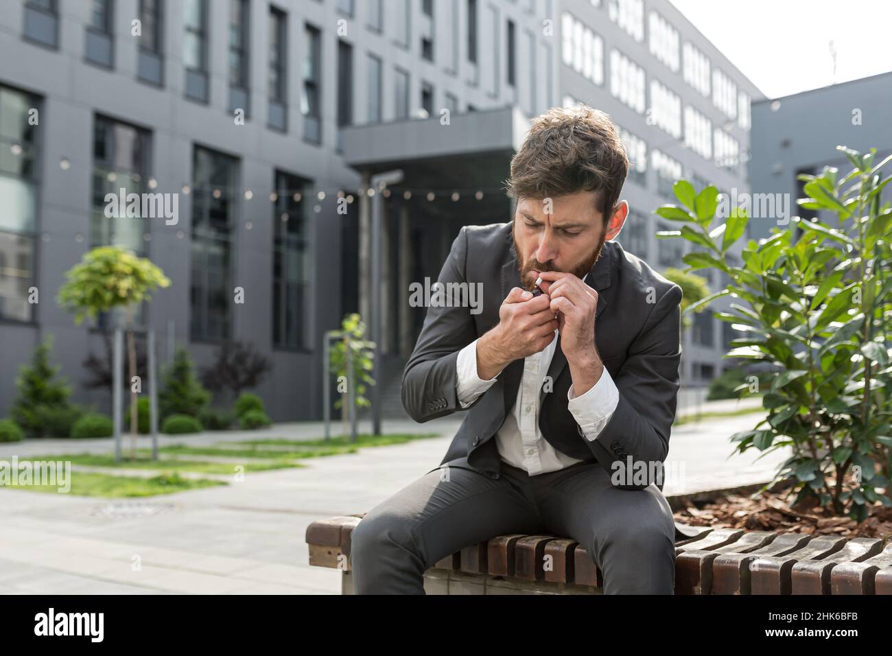 Male businessman smoking cigarette in the air near the office relieves ...