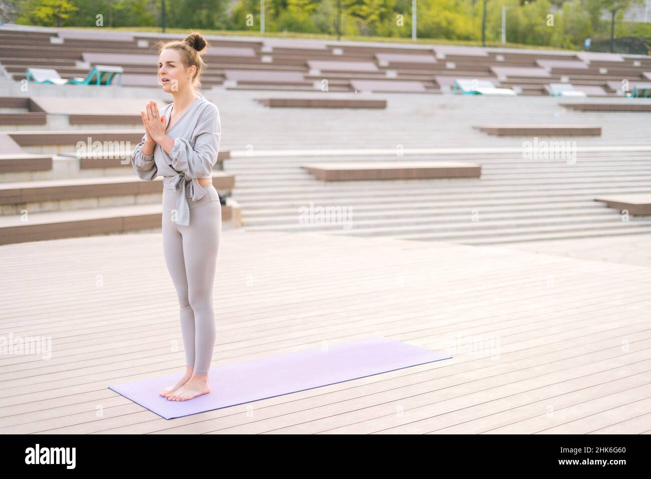 Wide shot of calm attractive Caucasian young woman practicing yoga ...
