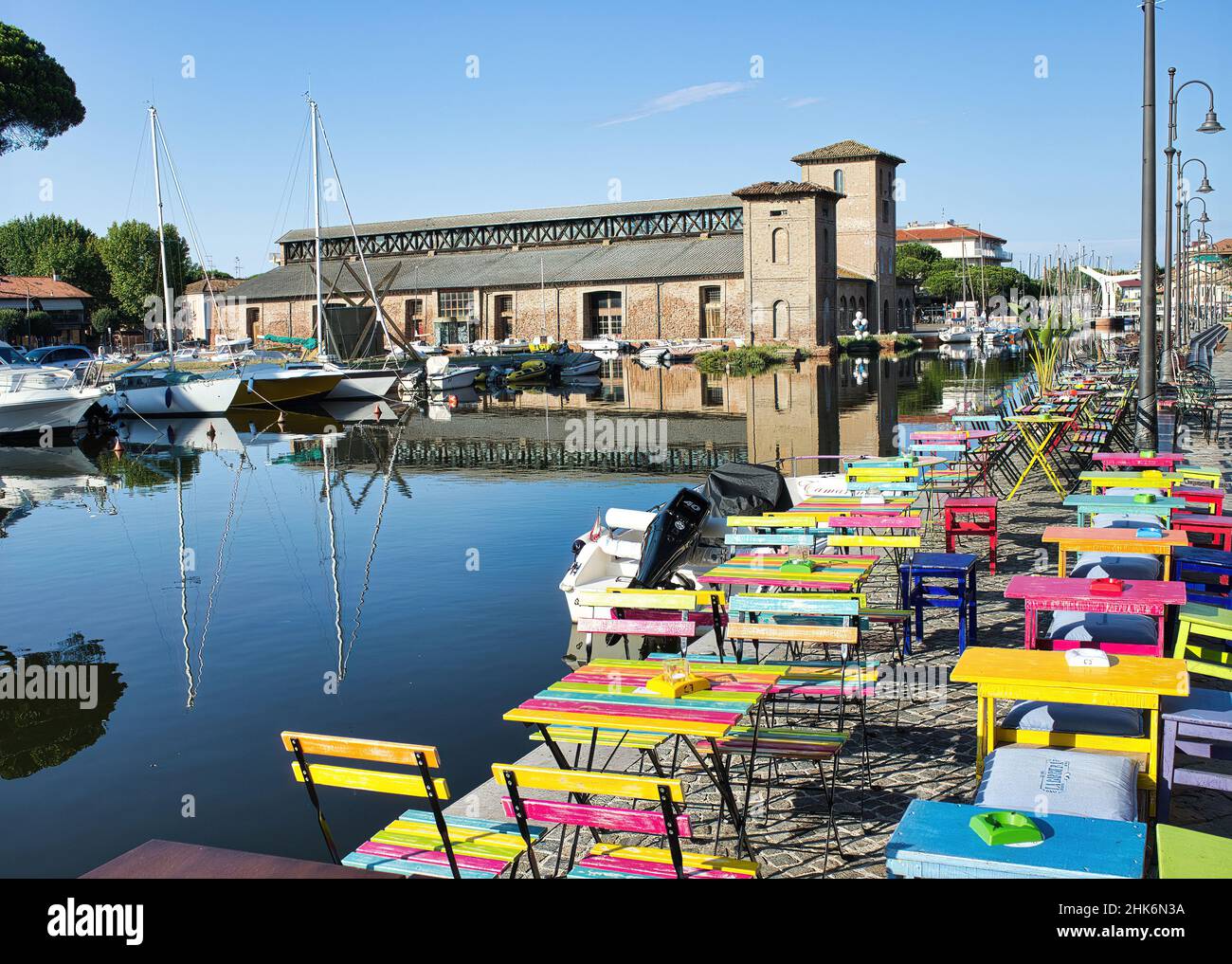 Salt warehouses and boats moored in the colorful canal port of Cervia ...