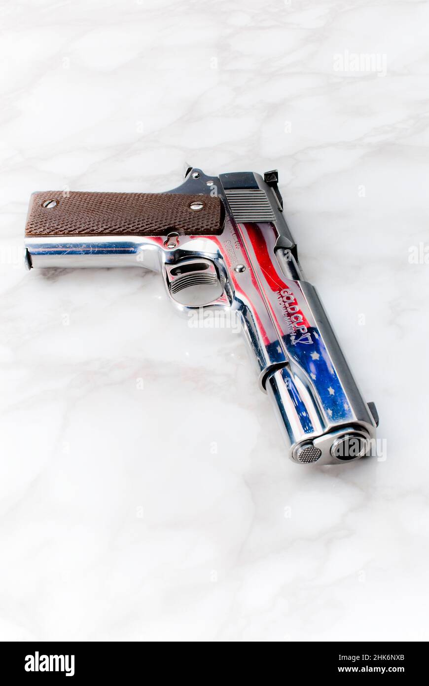 American flag reflected in barrel of a handgun laying on a marble ...
