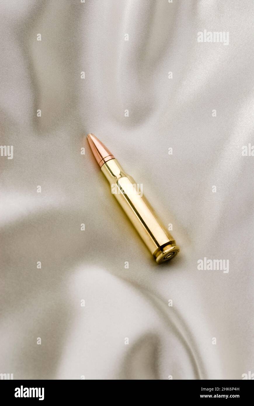 Single bullet laying on satin pillow Stock Photo - Alamy