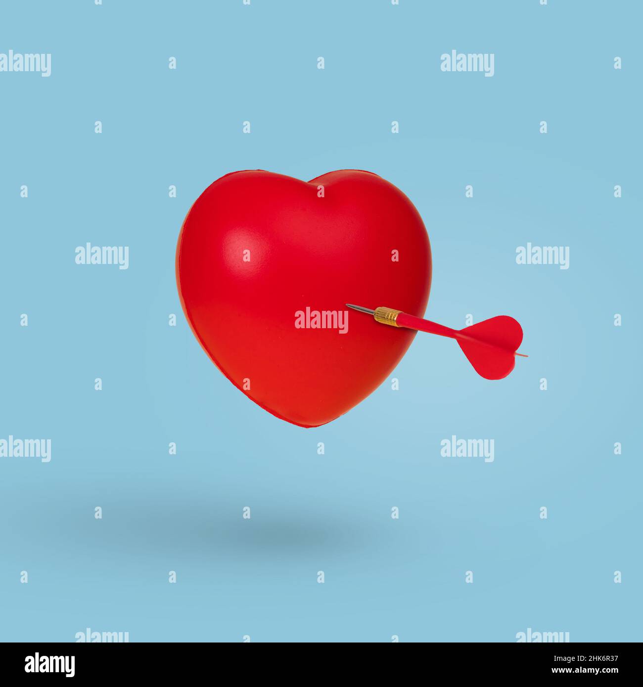 Dart hitting in a red heart, isolated on a blue background. Minimal ...