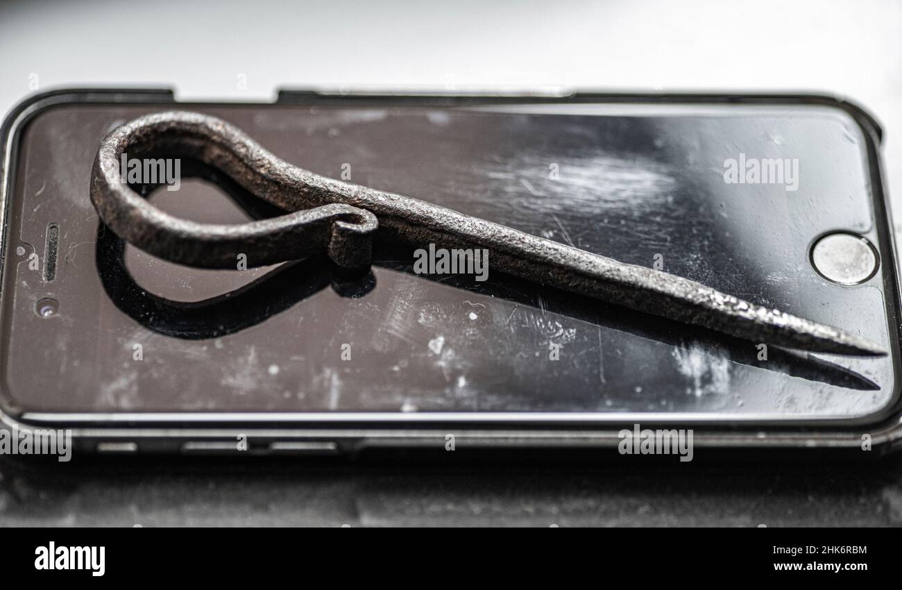 An ancient awl used in harness crafting, on a modern hi-tech smartphone ...