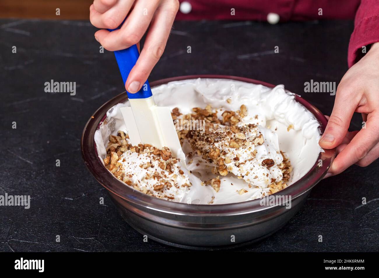 Mixing whipped egg whites with sugar and chopped nuts to make a smooth ...