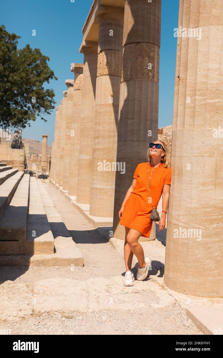 A woman stands in the ancient acropolis of Lindos against the ...