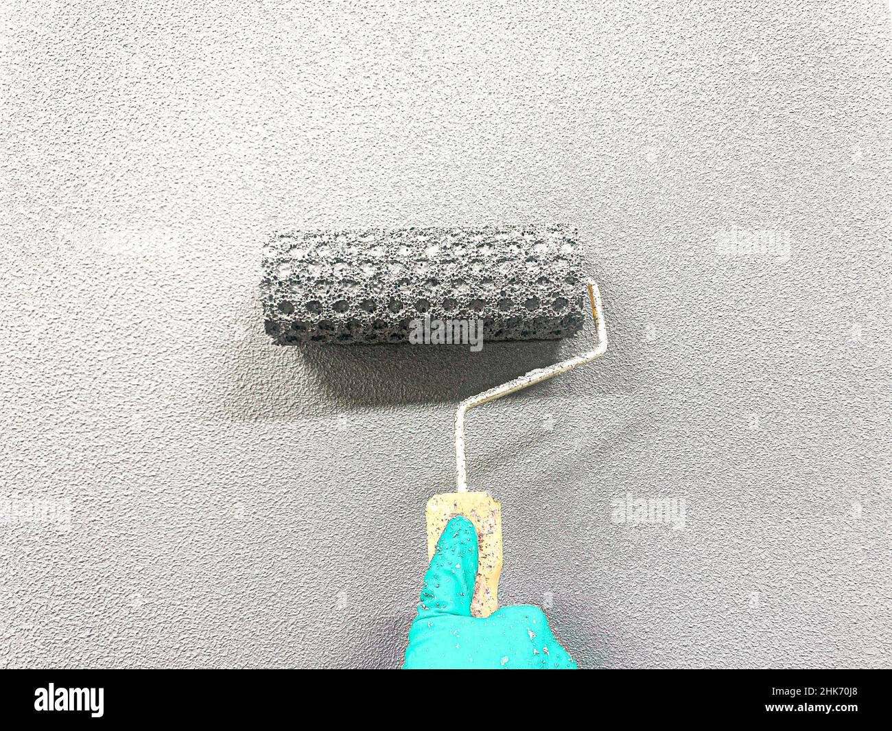 Paint roller paints the wall with structural paint Stock Photo - Alamy