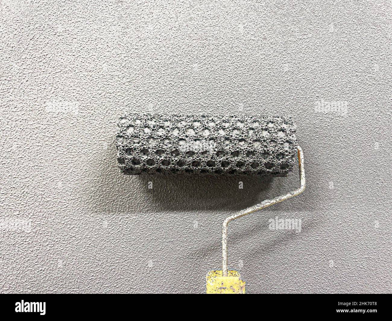 Paint roller paints the wall with structural paint Stock Photo - Alamy