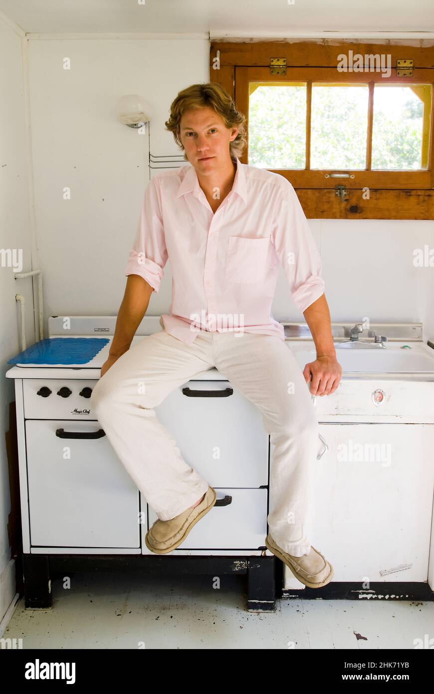 Young man sitting on stove Stock Photo - Alamy