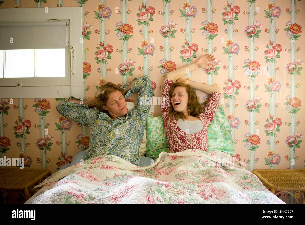 Young couple laying in bed stretching and yawning in bedroom with ...