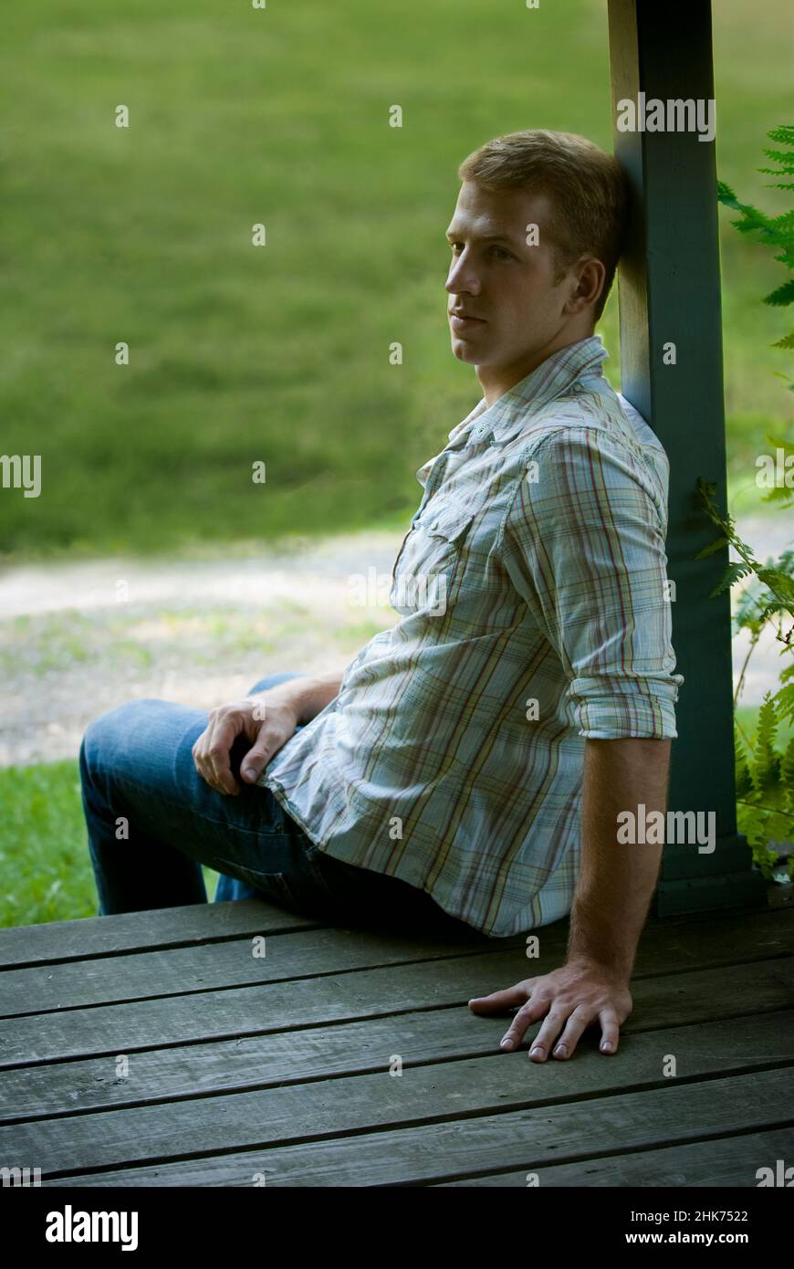 Young man seated on porch Stock Photo - Alamy