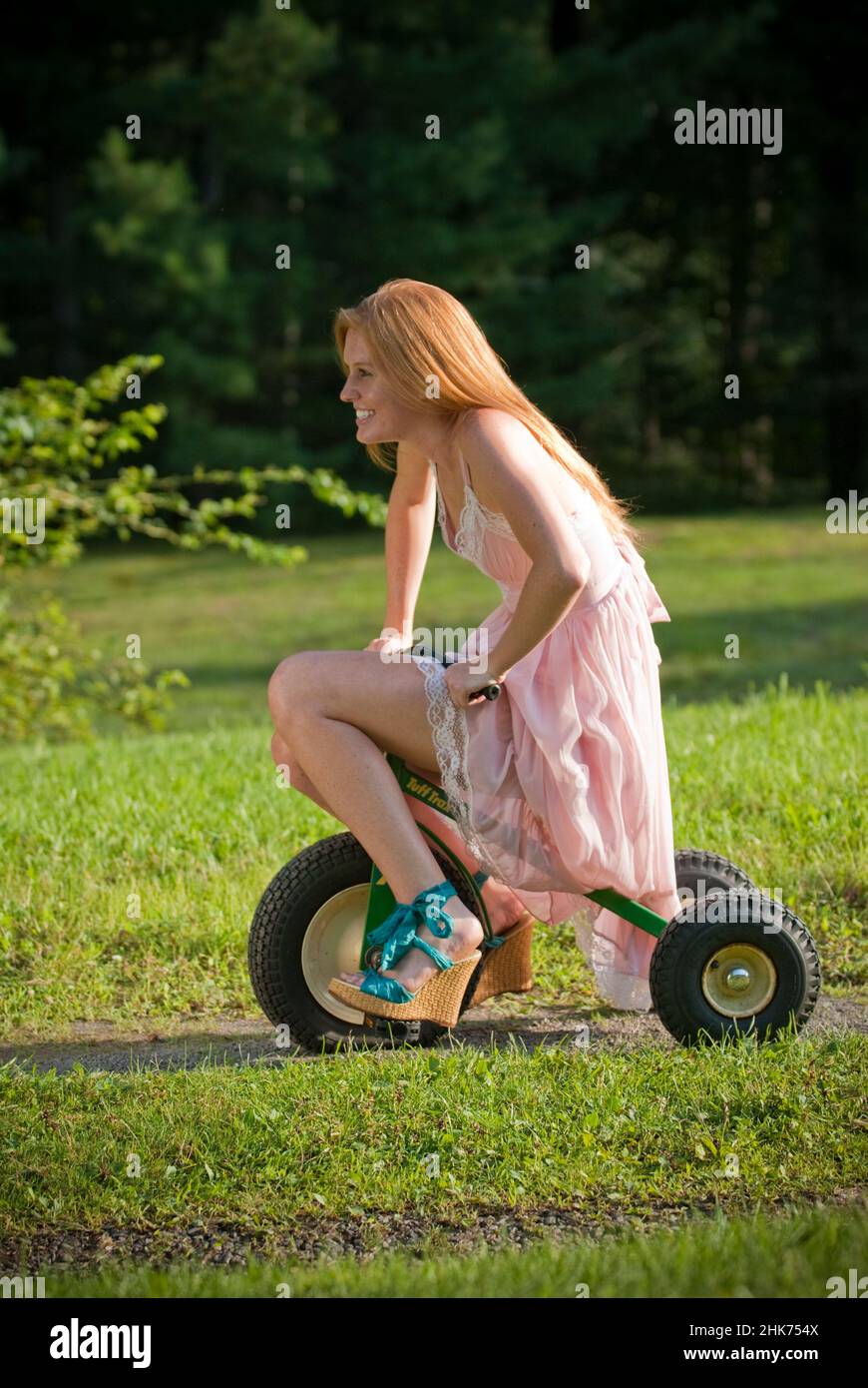 Young redheaded woman riding a child's tricycle Stock Photo - Alamy