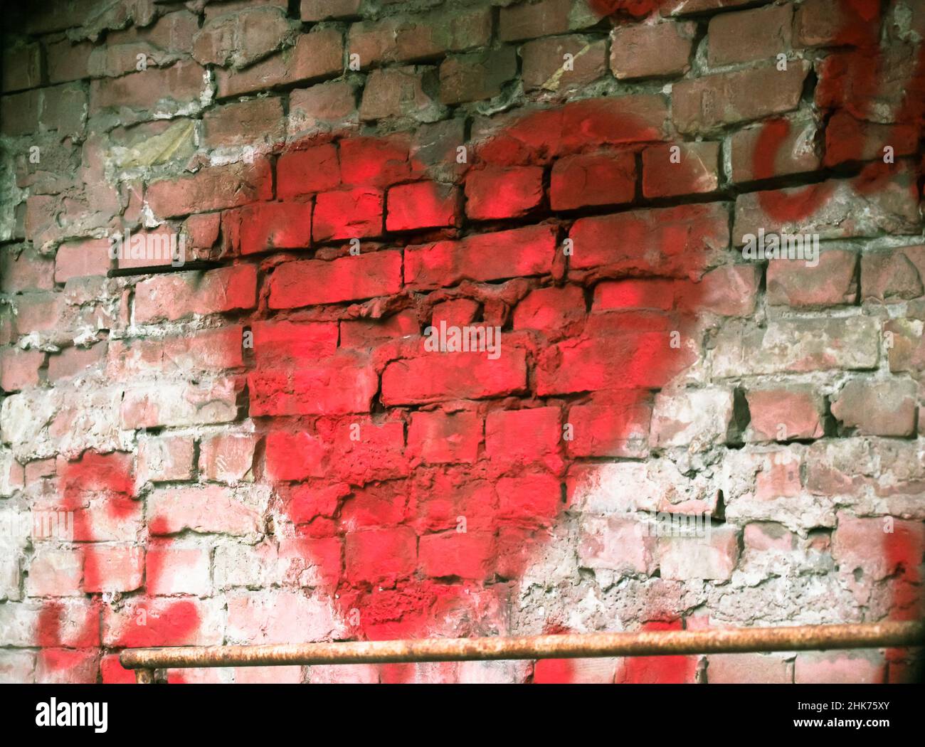 A big red heart painted on a red brick wall. Rough background with a ...