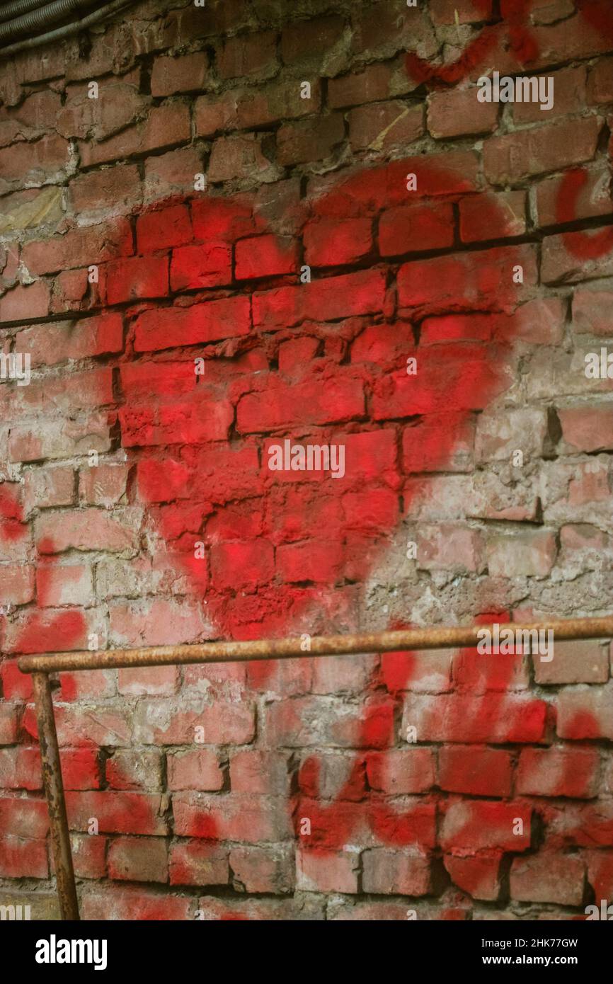 A big red heart painted on a red brick wall. Rough background with a ...