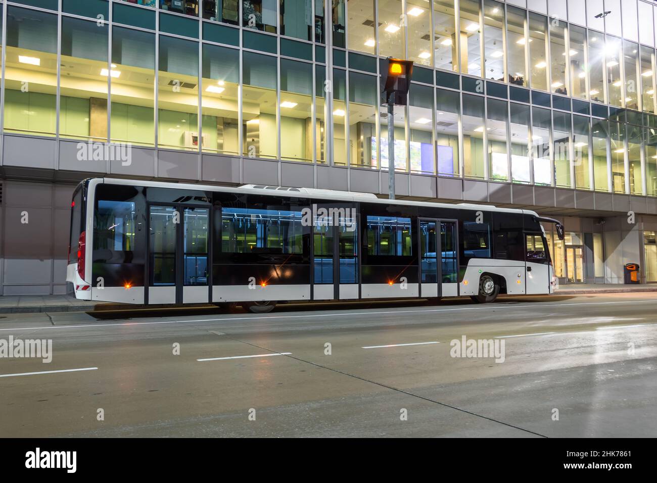 The bus stands at a stop at night against the background of the ...