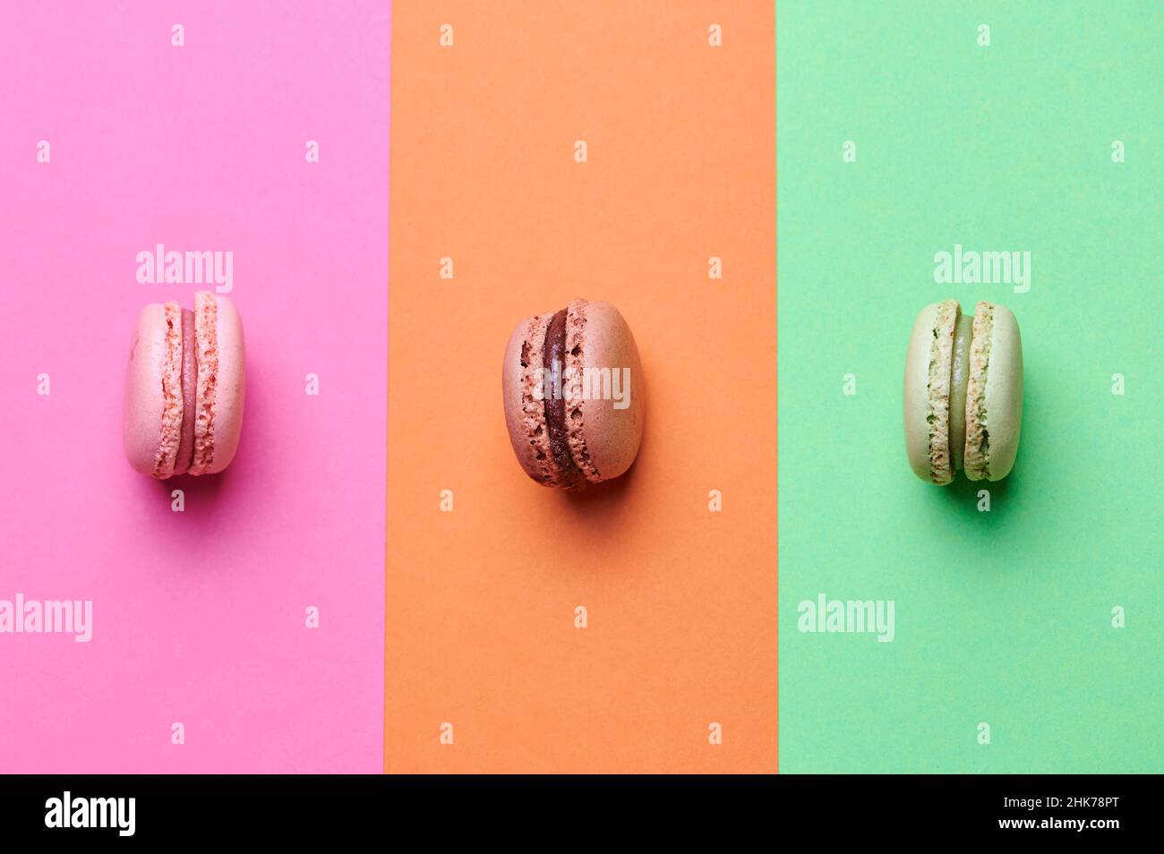 three colored macarons in pink, brown and green on matching colored ...
