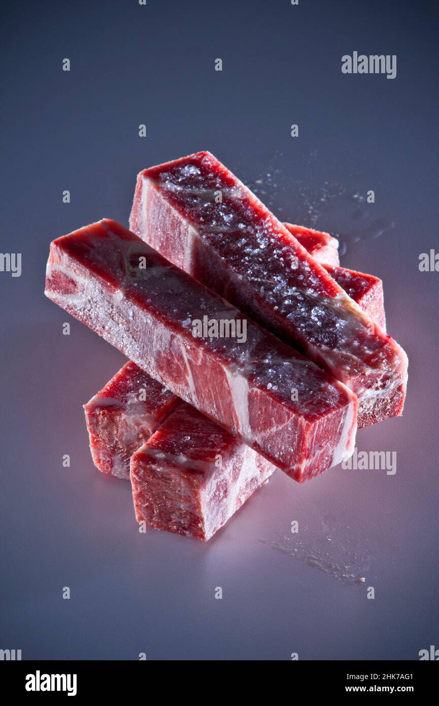 Rectangular cuts of frozen beef stacked on dark background Stock Photo ...