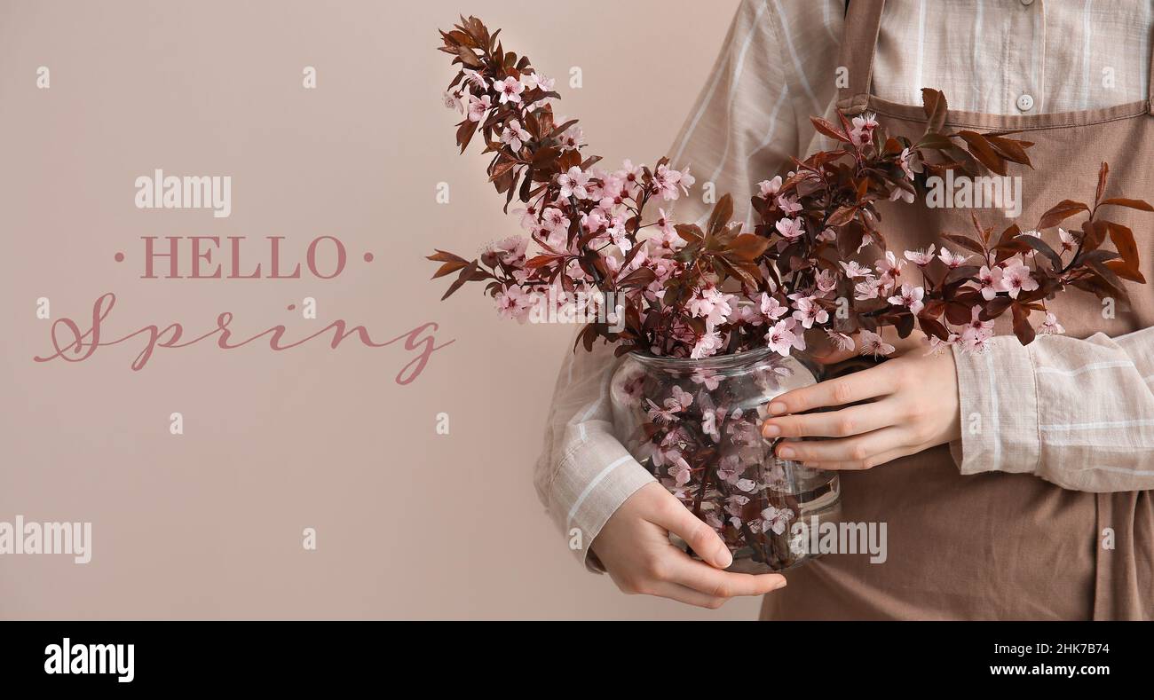 Woman with beautiful blossoming tree branches in vase on color ...