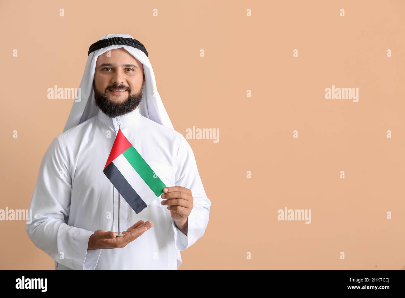 Man in traditional clothes and with the national flag of UAE on color ...