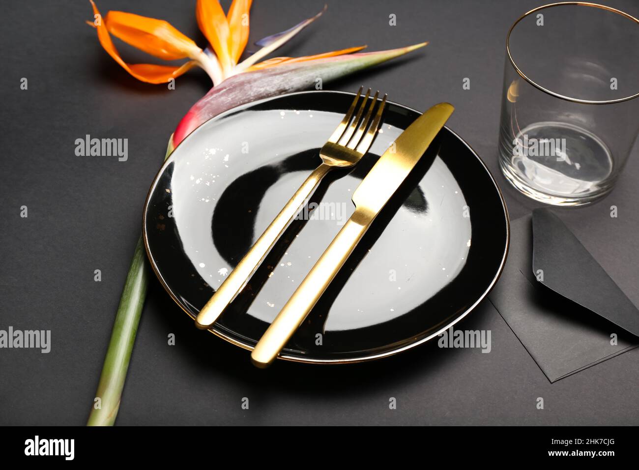 Simple table setting with bird of paradise flower on dark background ...