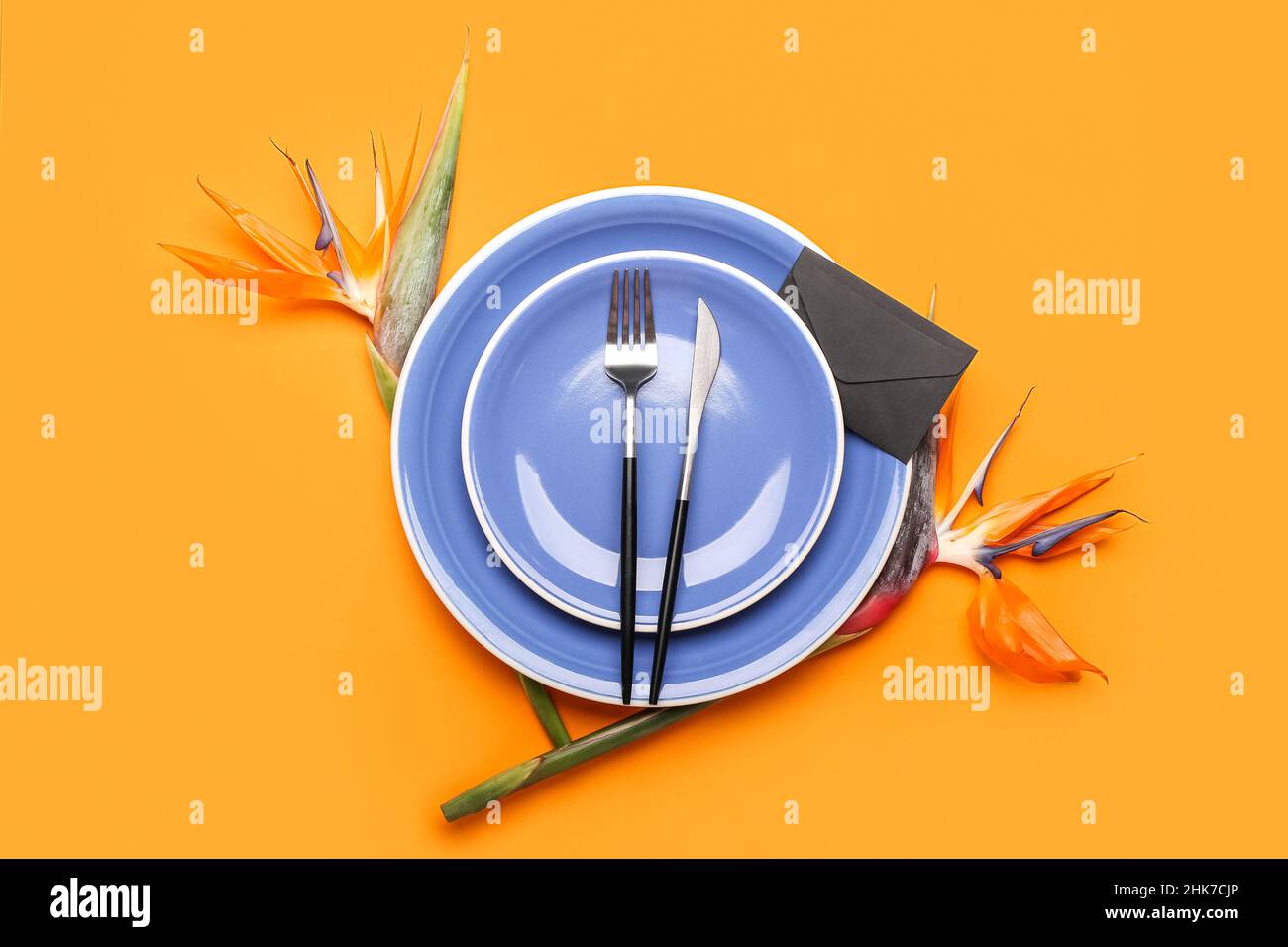 Simple table setting with bird of paradise flowers on orange background ...