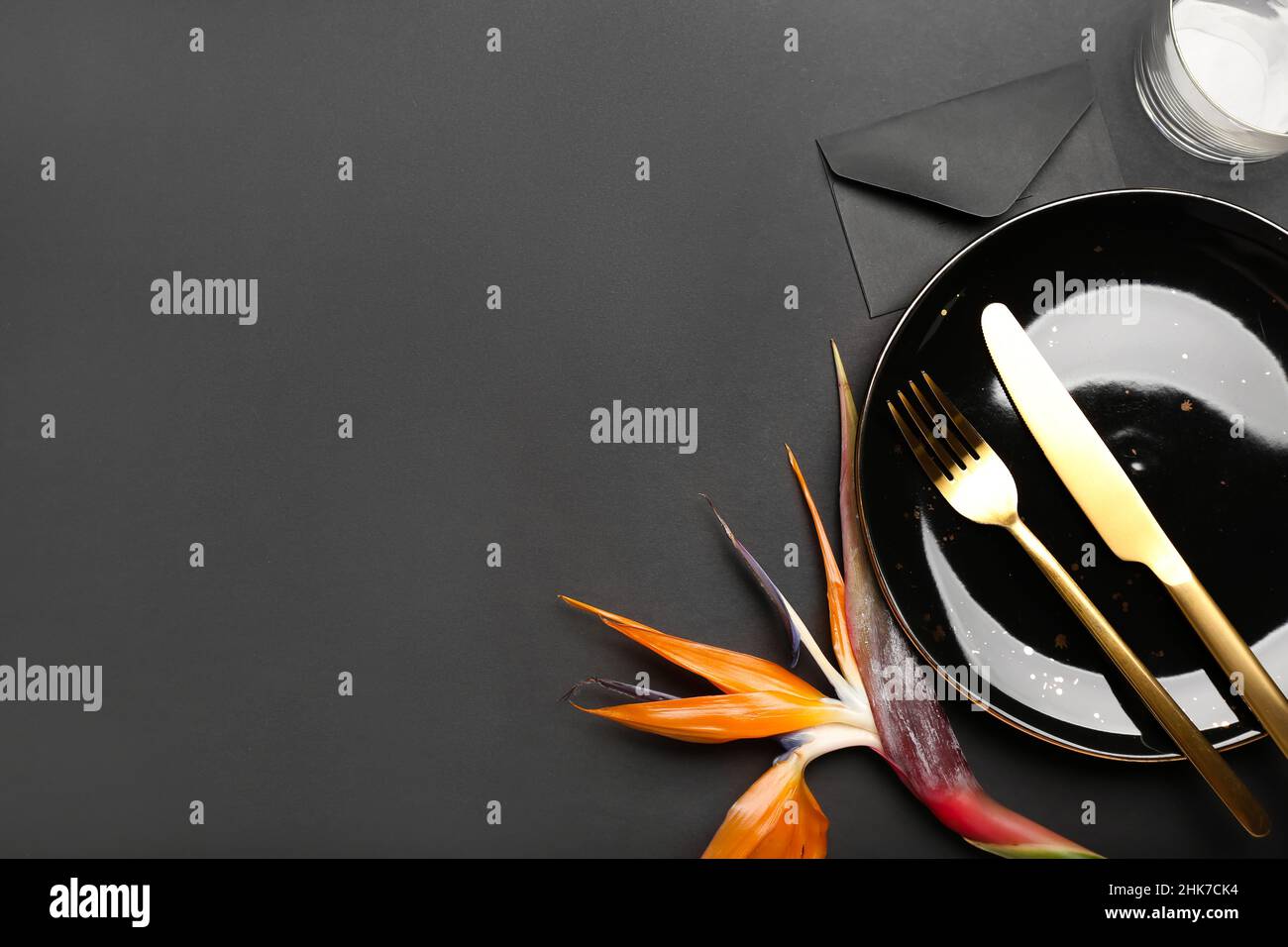 Simple table setting with bird of paradise flower on dark background ...