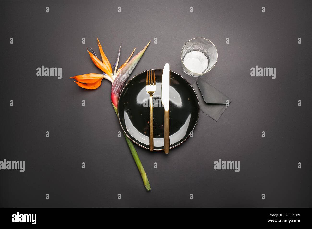 Simple table setting with bird of paradise flower on dark background ...