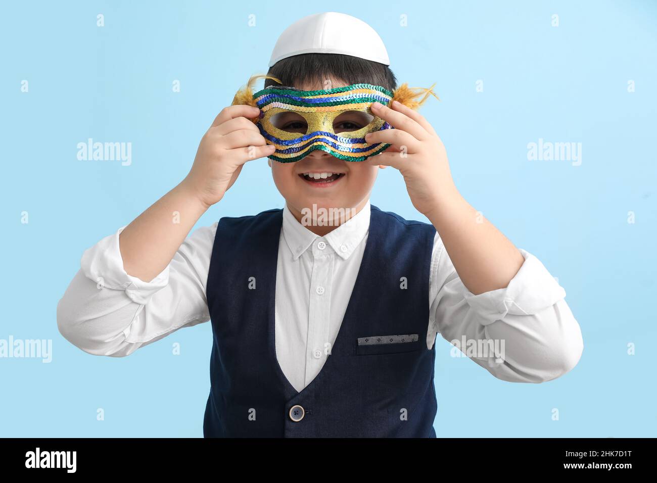 Little Jewish boy with carnival mask for Purim holiday on color ...