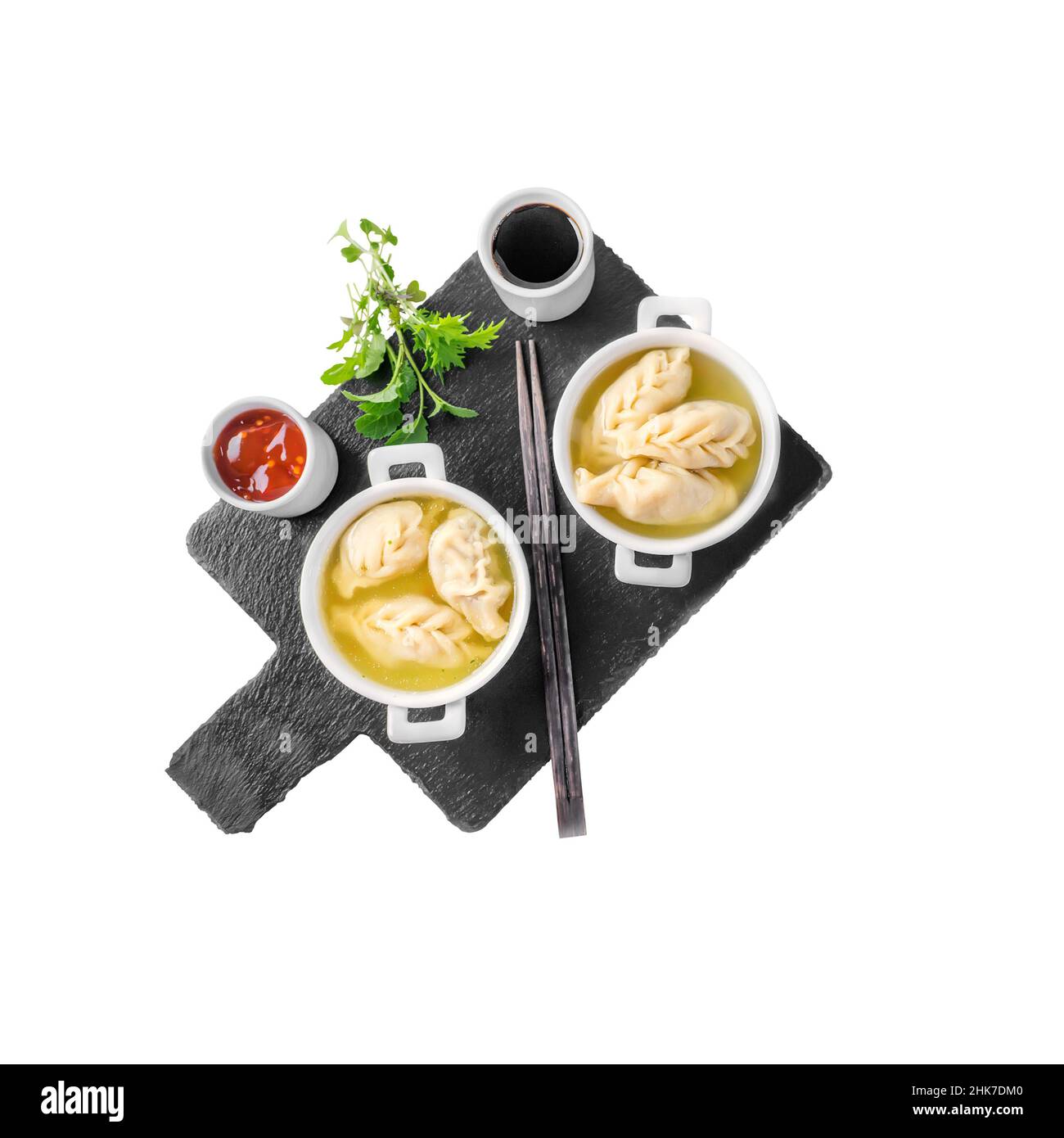 Dumplings are served in white cups with sauces on a serving board . Top ...