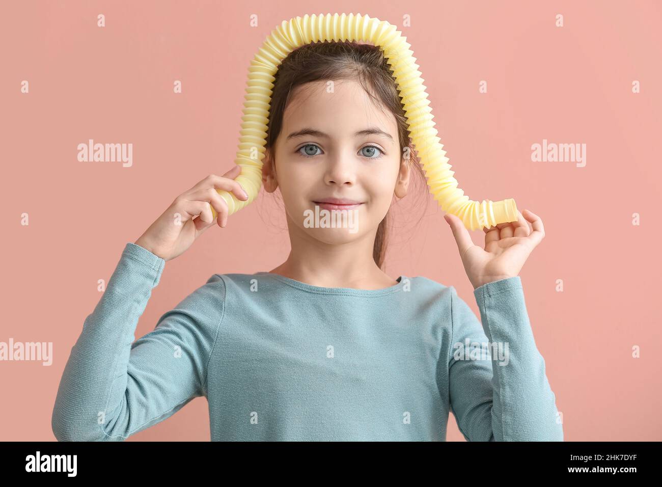 Funny little girl with yellow Pop Tube on pink background Stock Photo ...