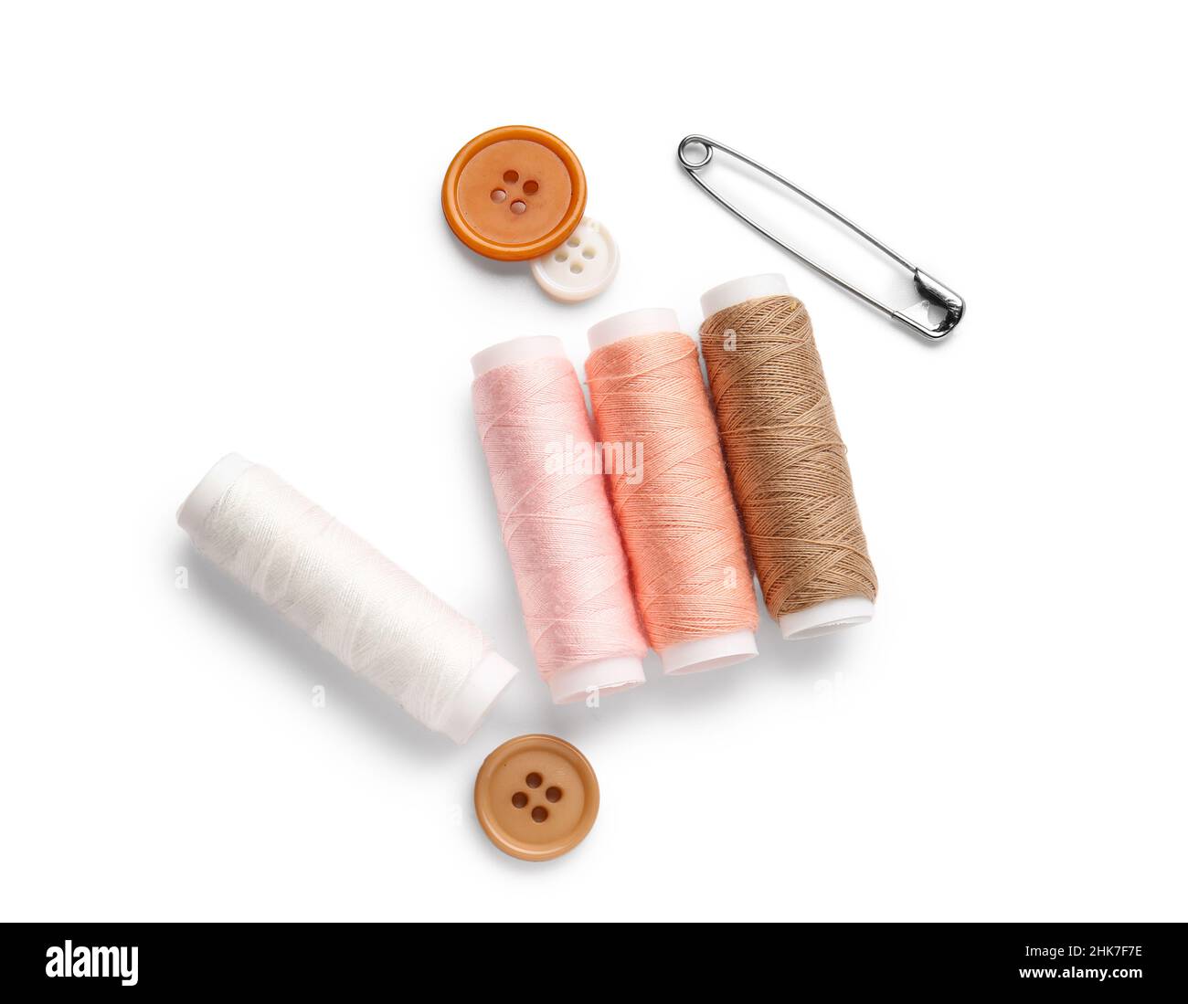 Thread spools with buttons and pin on white background Stock Photo - Alamy
