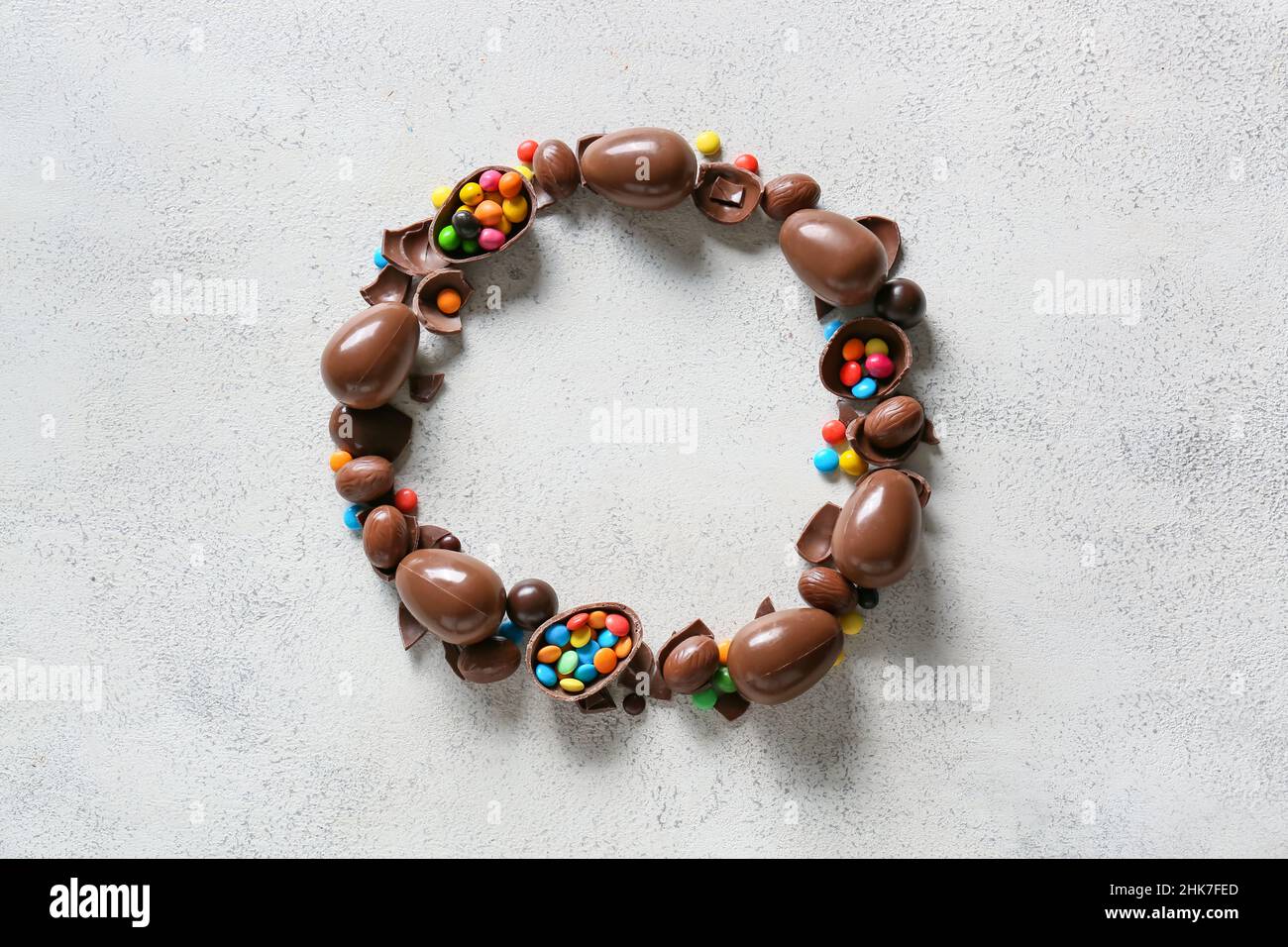 Frame made of chocolate Easter eggs with candies on light background ...