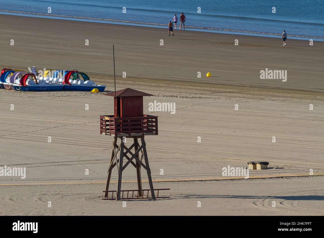 large beach with colorful pedal boats and a watchtower in the ...