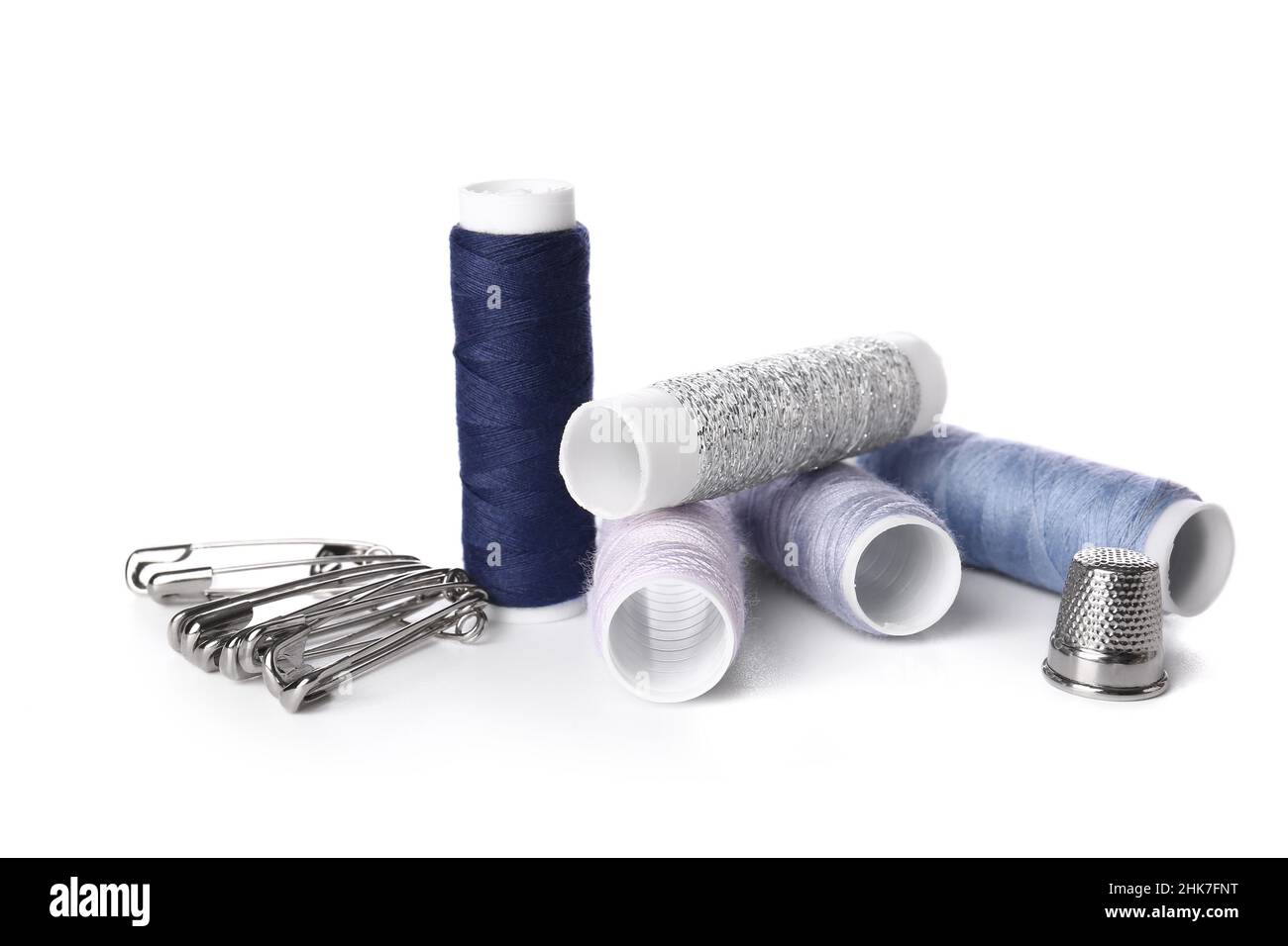 Different thread spools, safety pins and thimble on white background ...