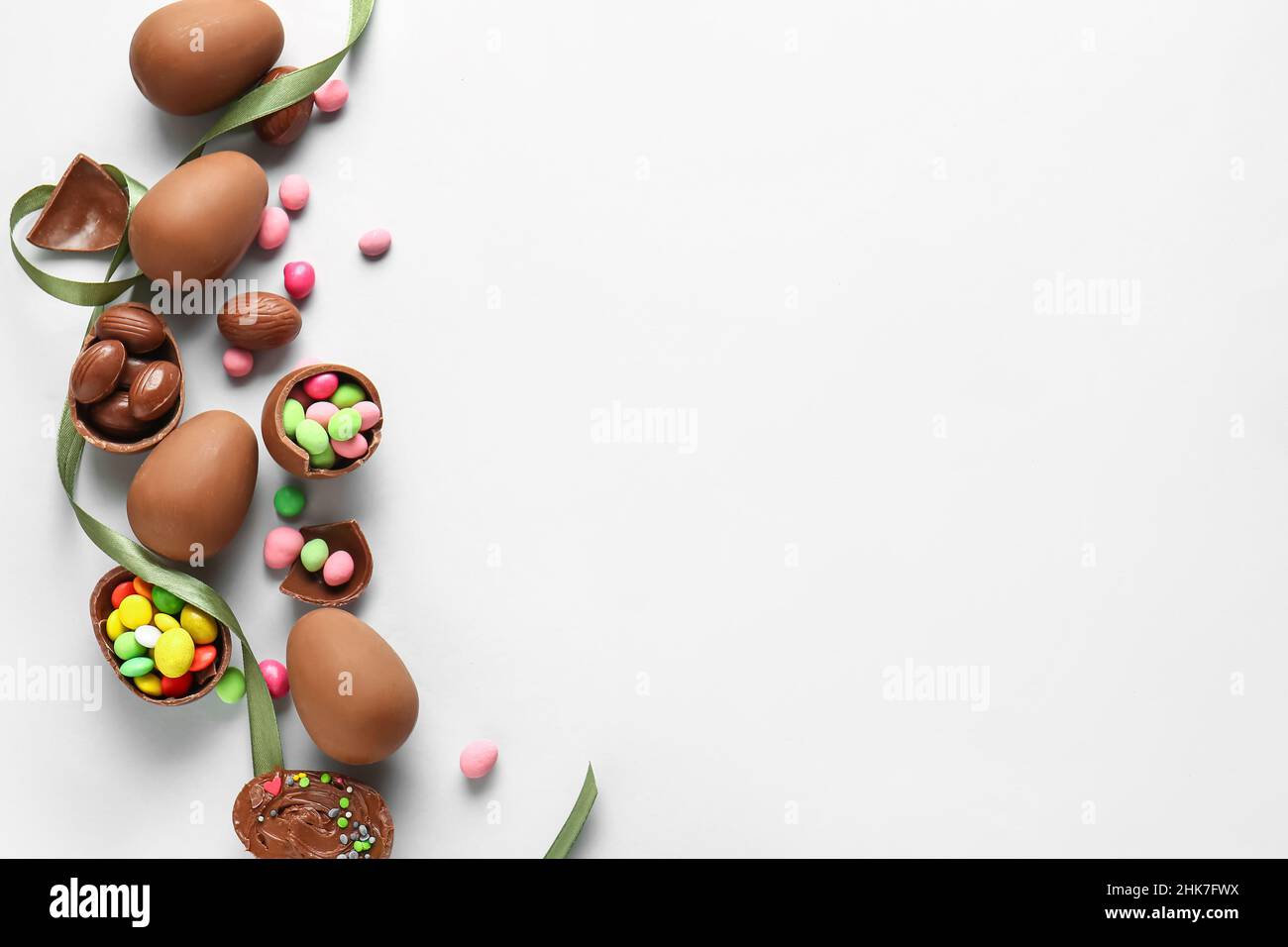 Composition with broken chocolate Easter eggs and different candies on light background Stock ...