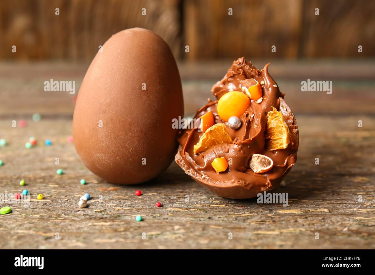 Broken chocolate Easter egg with different candies on wooden table, closeup Stock Photo - Alamy