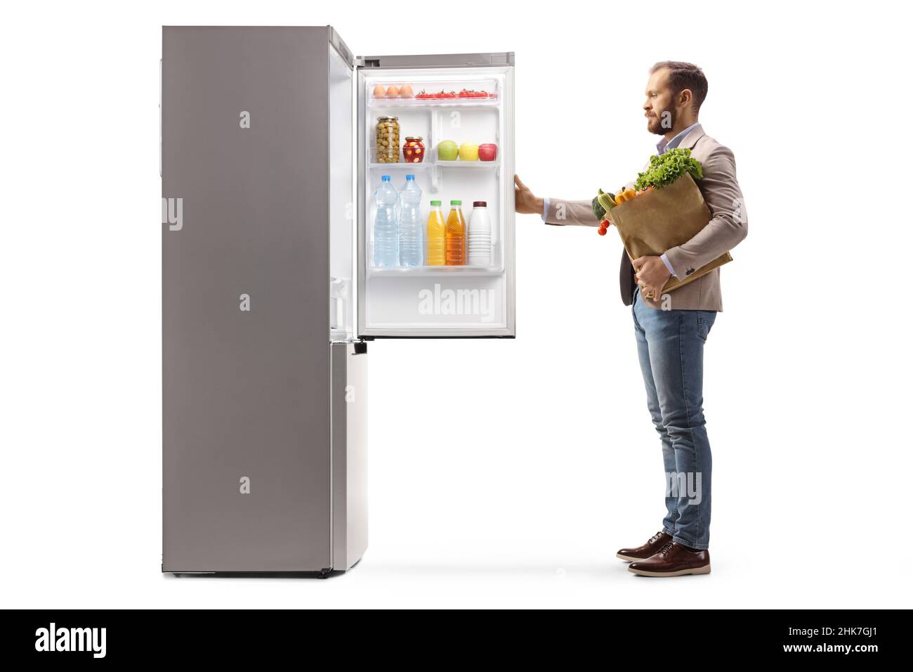 Full length profile shot of a man opening a fridge and holding a ...