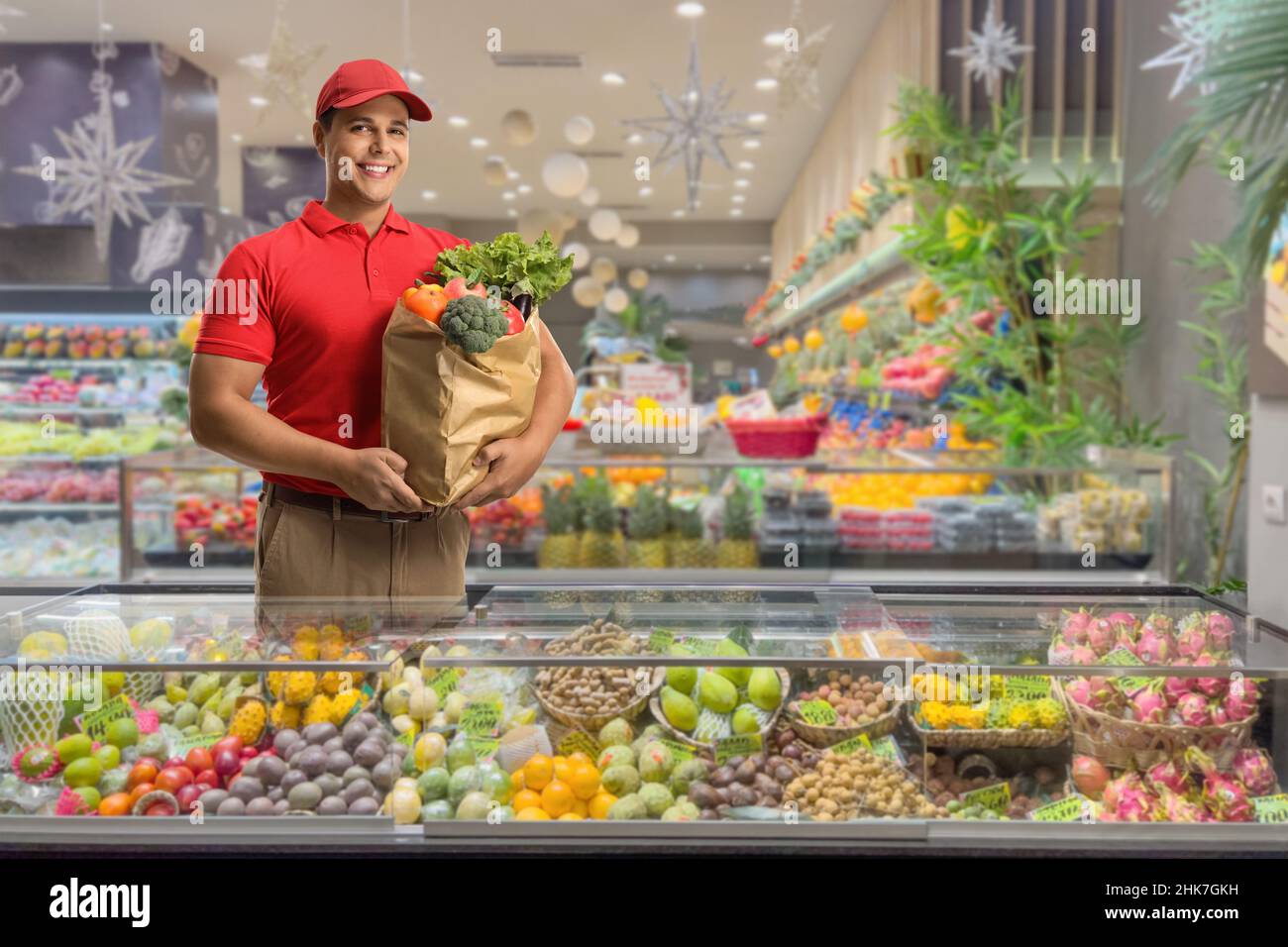 Shop assistant in a grocery behind a counter with fruits and vegetables ...
