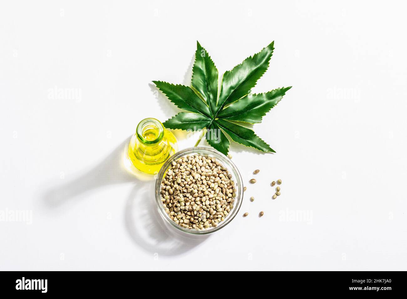 Ripe hemp seeds, oil, and artificial hemp leaf isolated on white ...